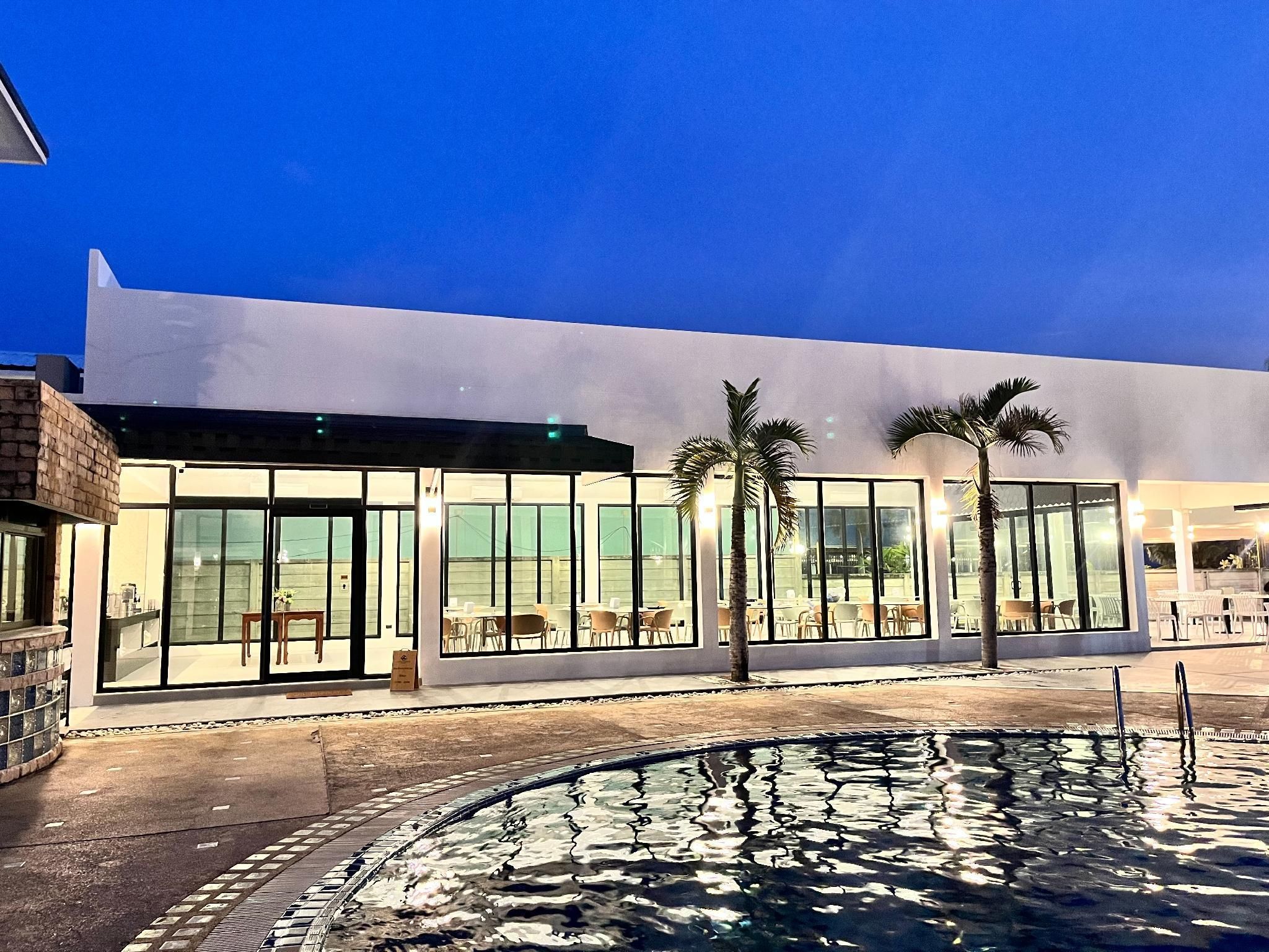 Um edifício moderno com grandes janelas de vidro, área de estar ao ar livre e espaço para piscina.