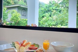Mesa de café da manhã com um prato de comida, um copo de suco de laranja e uma tigela.