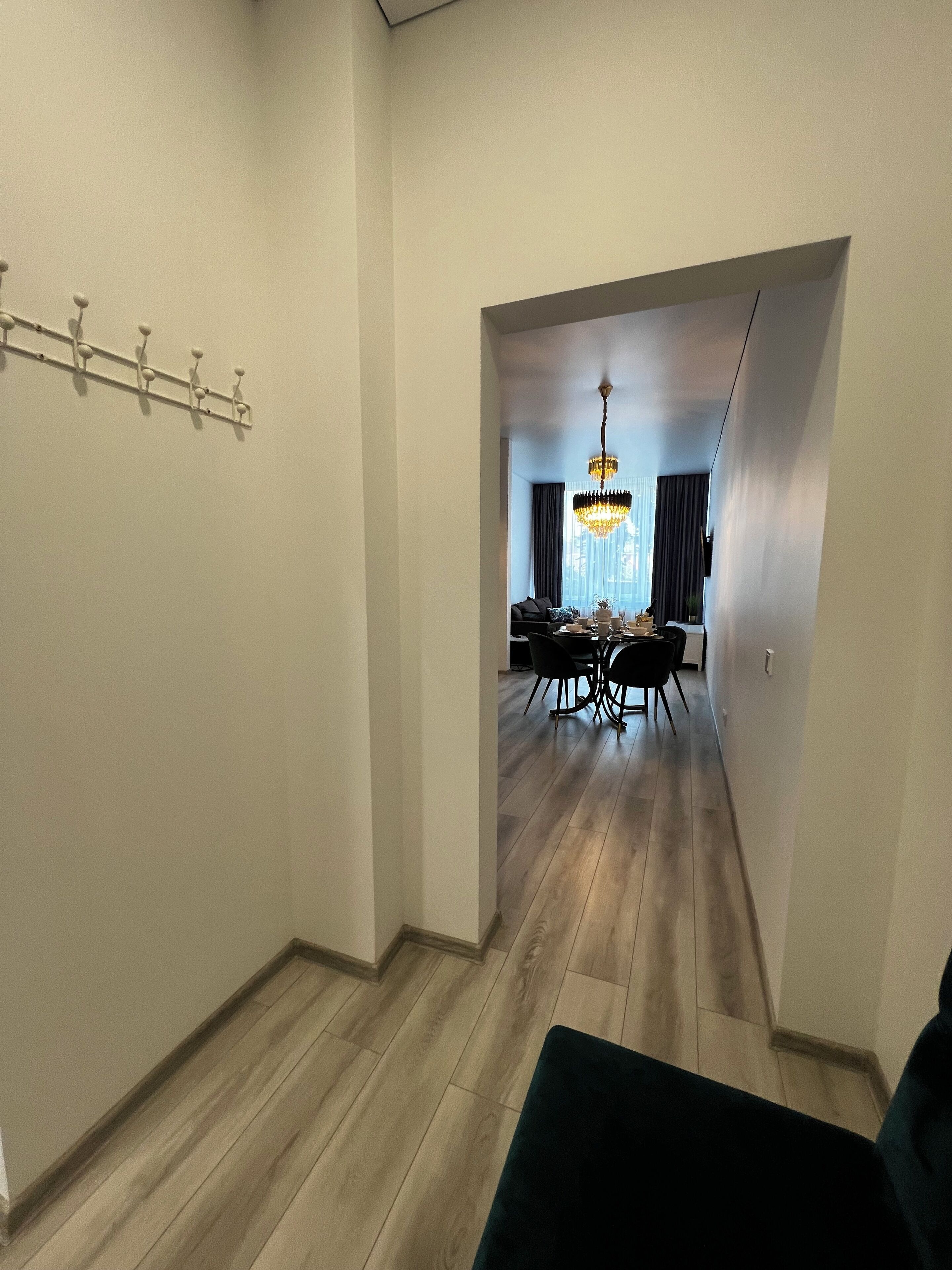 Um interior moderno com área de jantar, um candelabro e um porta-roupas.