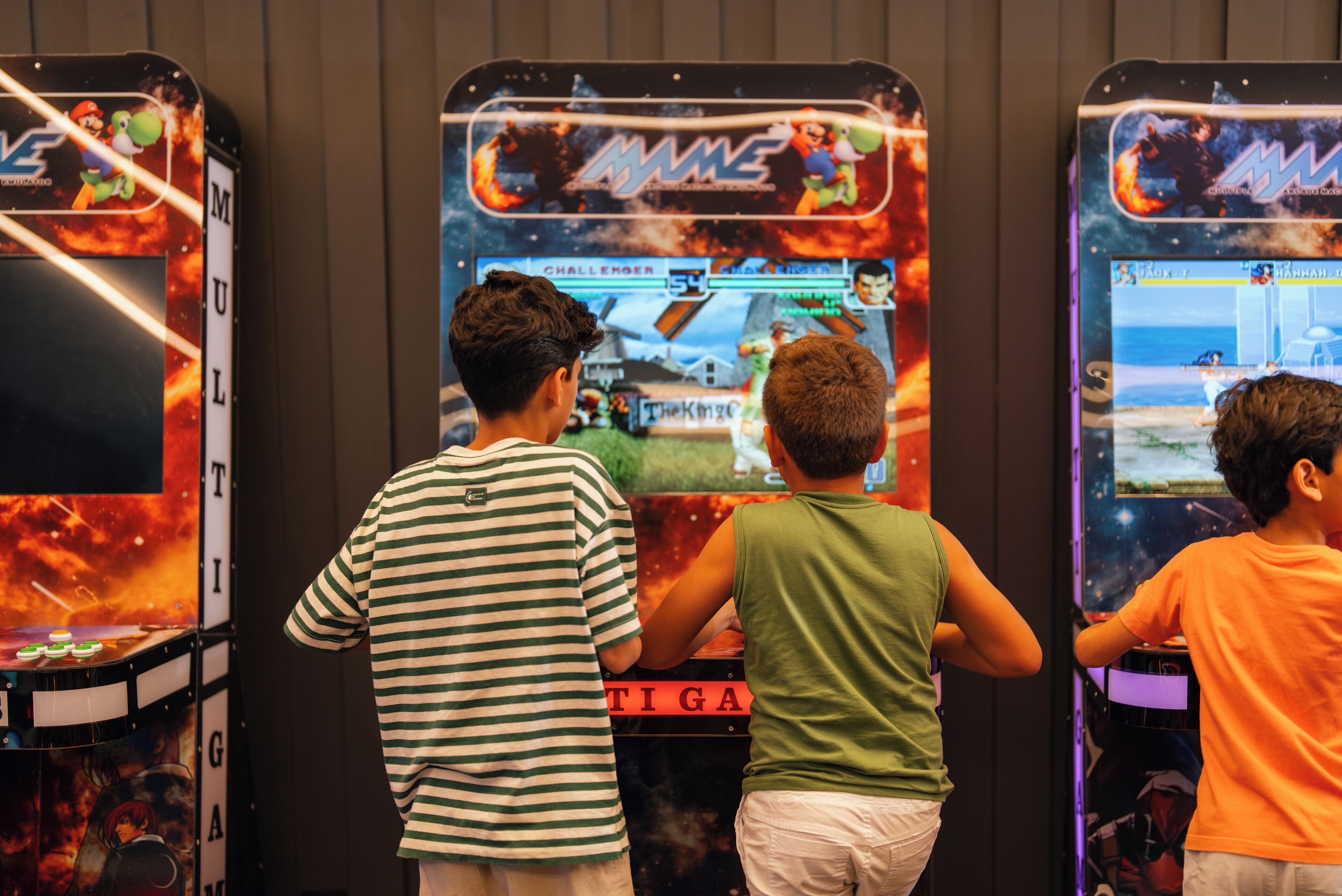 Um salão de jogos eletrônicos com várias telas exibindo diferentes jogos.