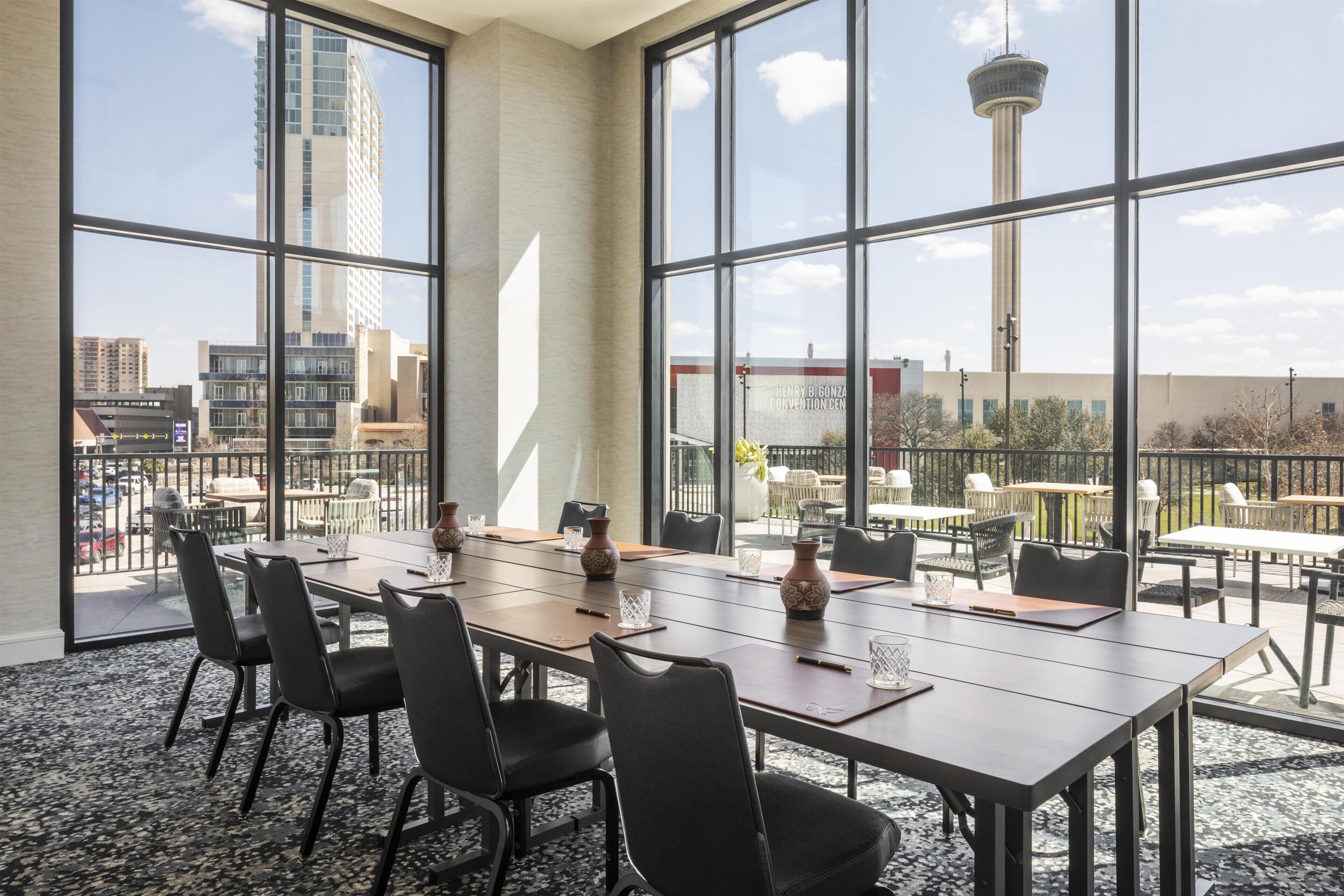 Uma sala de conferências com uma mesa grande e cadeiras, janelas amplas com vista para a cidade e design de interiores moderno.