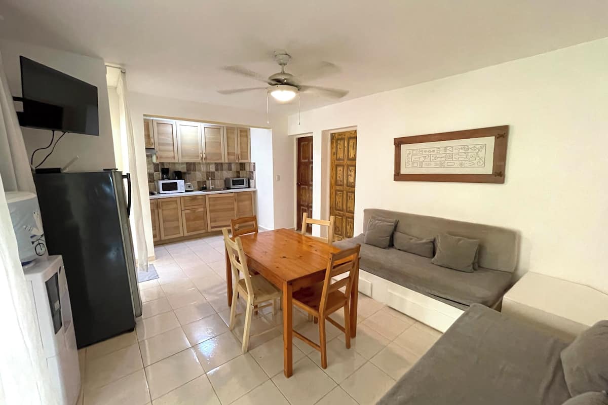 Espaço compacto com área de refeições, cozinha compacta e sofá cinza.