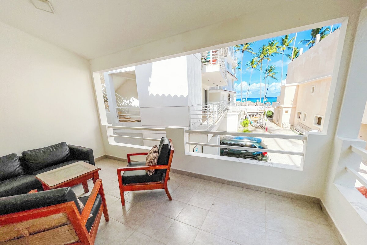 Uma varanda com vista para a praia e palmeiras.
