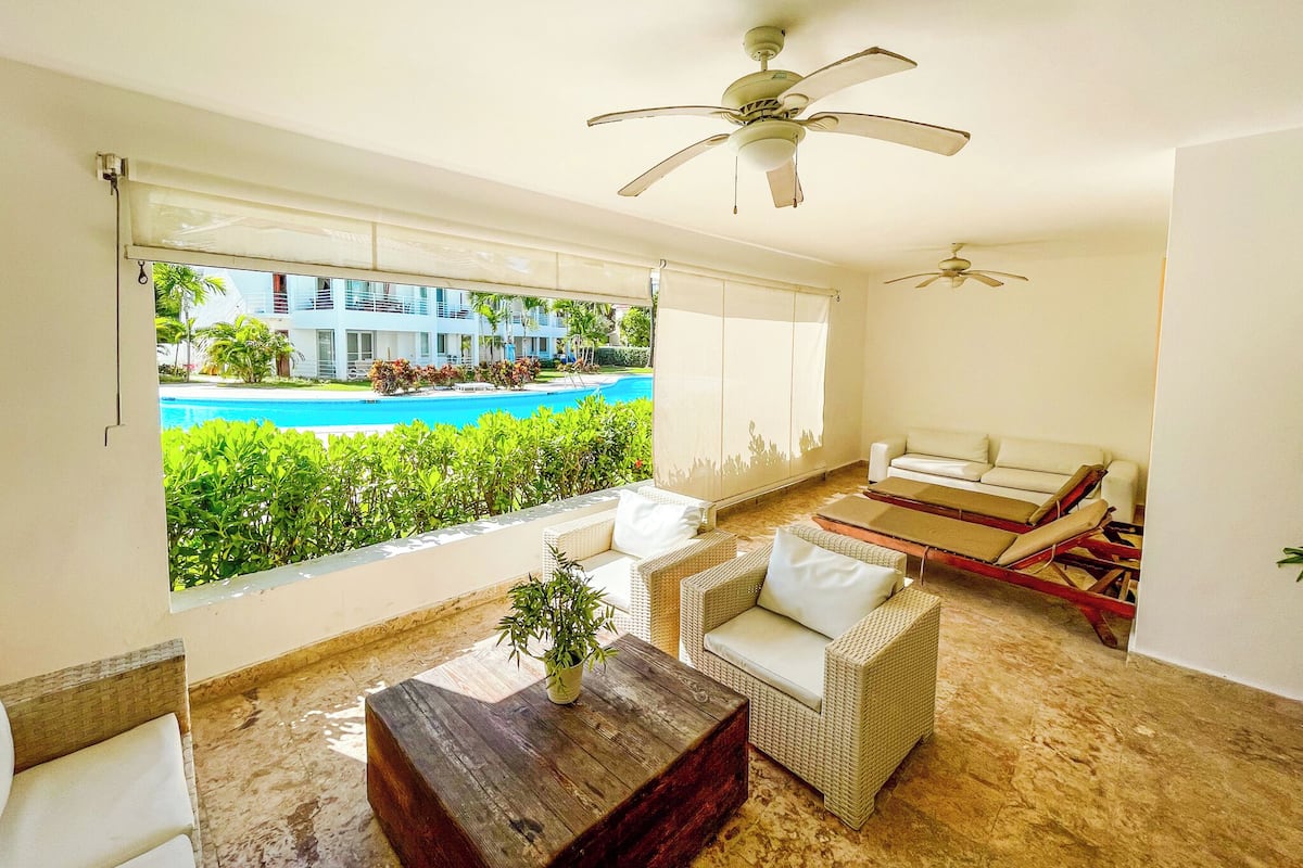 Quarto com vista para uma piscina, ventilador de teto e um sofá.