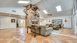 Uma sala de estar espaçosa com lareira, um grande candelabro e teto alto com claraboias.