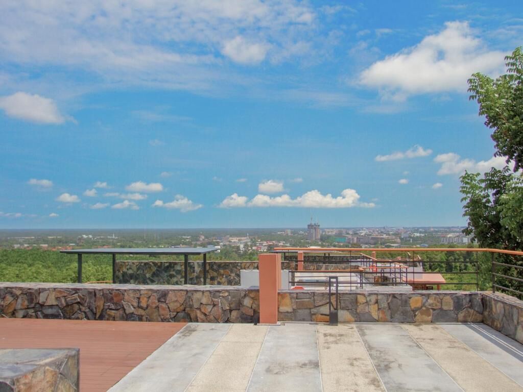 Terraço no telhado com parede de pedra, guarda-corpo de metal e vista da paisagem urbana ao longe.