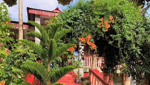 Uma escadaria com degraus vermelhos que levam a um edifício com telhado vermelho e paredes brancas.
