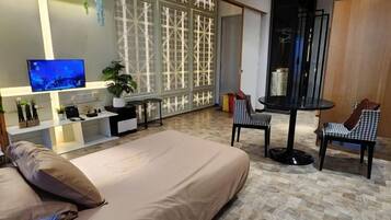 Quarto de hotel moderno com cama, escrivaninha, cadeira, TV e decoração na parede.