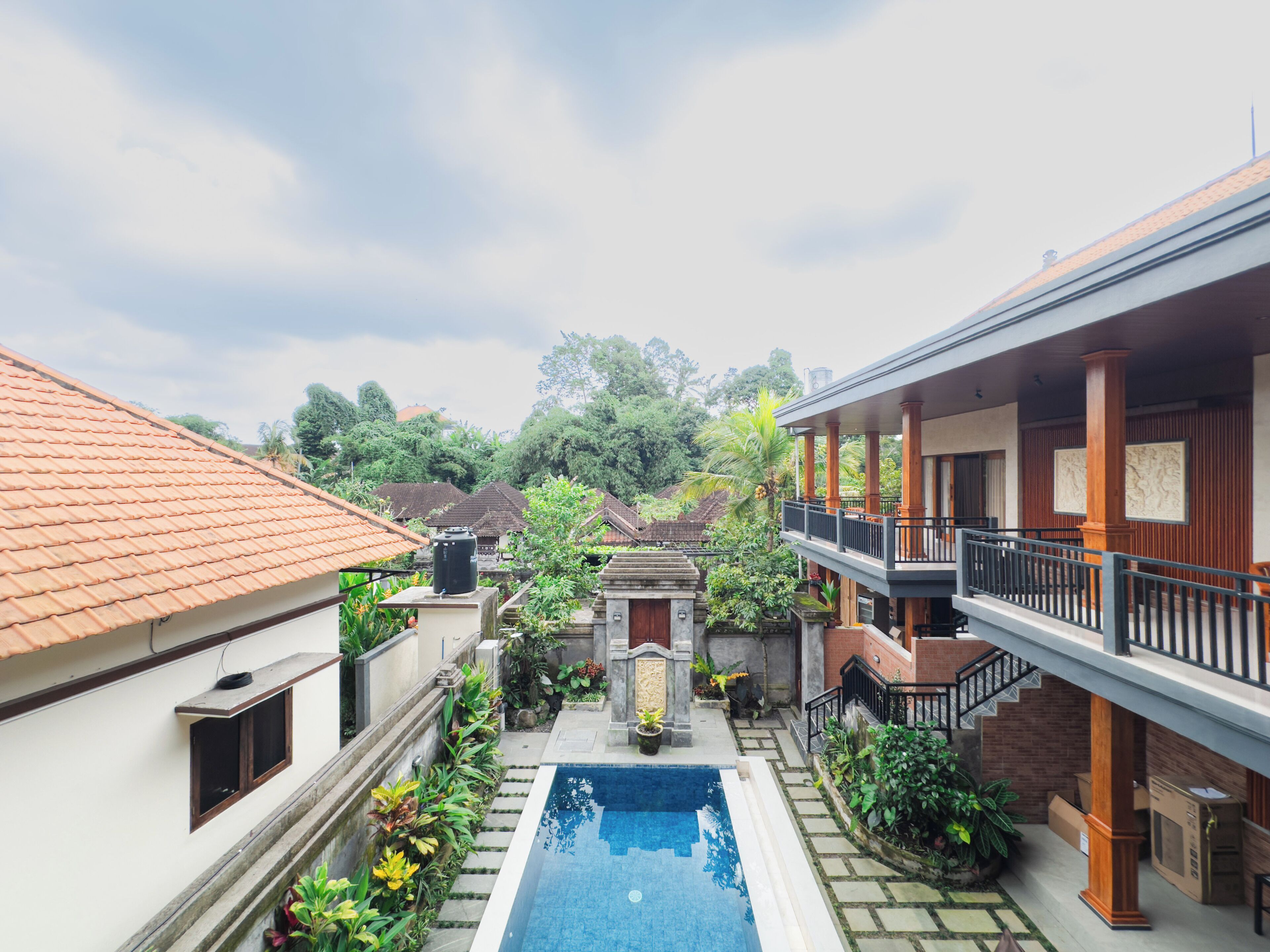 Um pátio com piscina, arquitetura tradicional e vegetação exuberante.