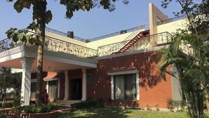 Uma casa de dois andares com varanda coberta, fachada de tijolo e um jardim bem cuidado.