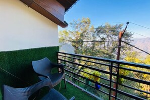 Varanda com grade de metal, uma cadeira e uma mesa pequena.