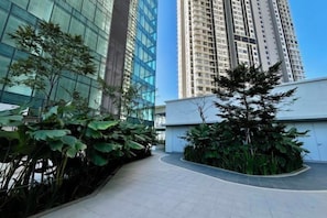 Edifício moderno com fachada de vidro, rodeado por vegetação e um caminho pavimentado.