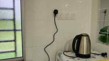 Cozinha com micro-ondas, chaleira e régua de tomadas sobre o balcão.