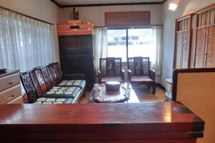 Quarto tradicional com mesa de madeira, sofá e cadeiras.