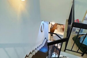 Uma escada com corrimão e um arandelar circular na parede.