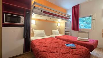 Quarto de hotel compacto com duas camas, micro-ondas, mini-geladeira e janela com cortinas.