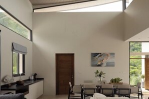 Interior moderno com área de jantar, cozinha e uma janela ampla.