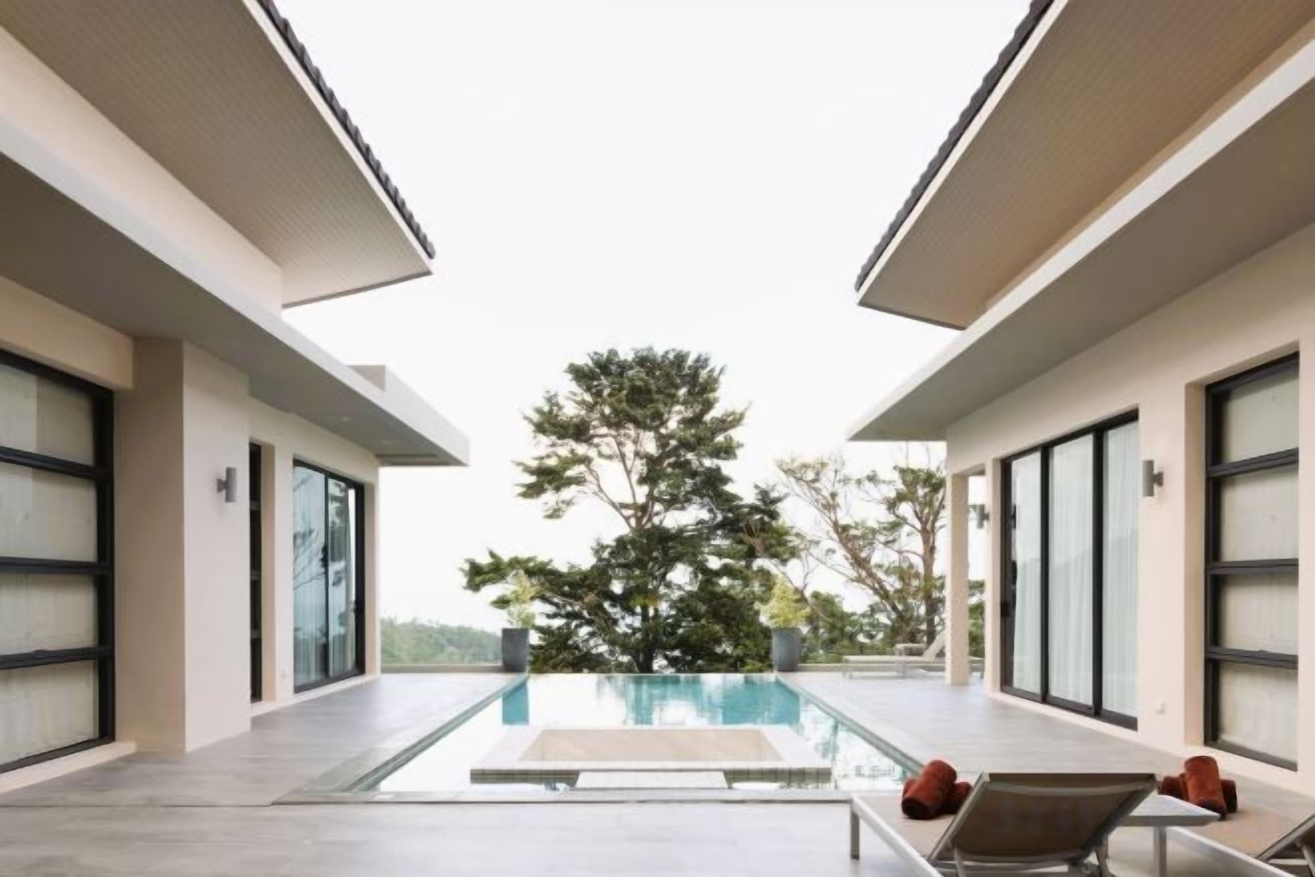 Uma área de piscina moderna com vista clara do céu, uma grande árvore e design minimalista.