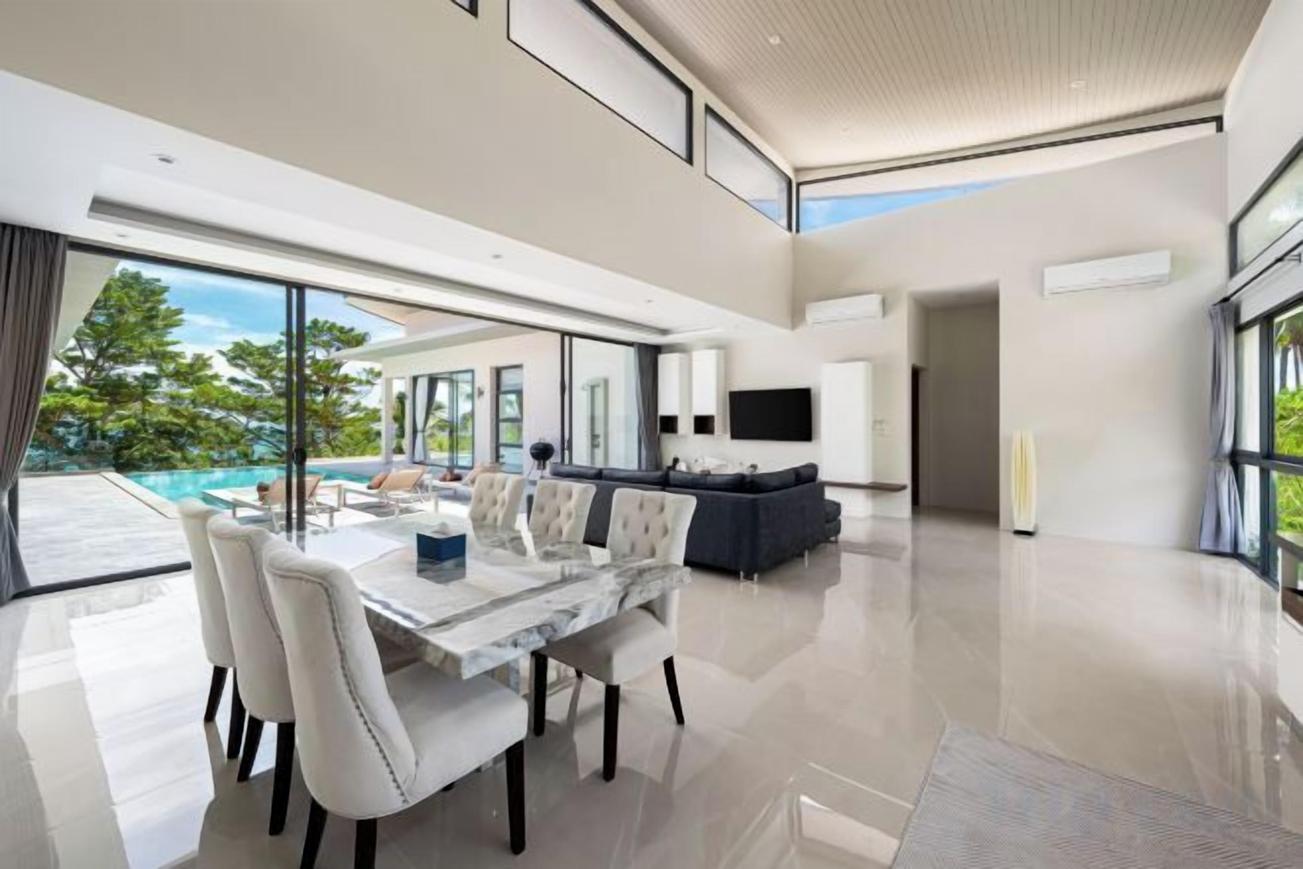 Espaço moderno com área de jantar, cozinha e vista para uma piscina.