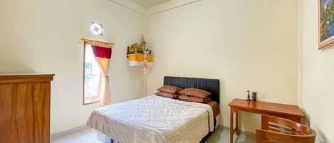 Quarto com cama, escrivaninha de madeira, cadeira, guarda-roupa e janela com cortinas.