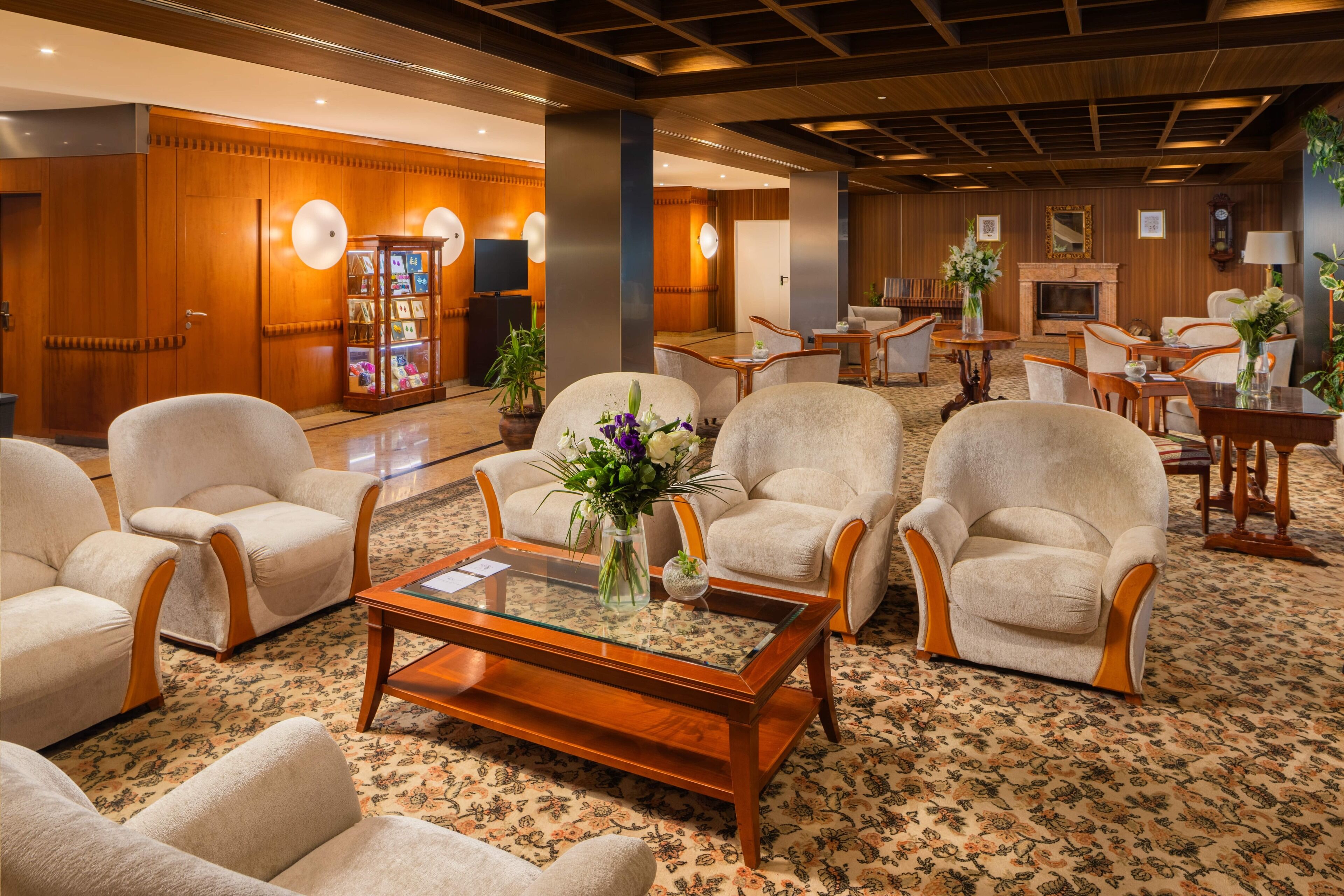 Um hall com poltronas confortáveis, uma mesa de centro de vidro e uma lareira.