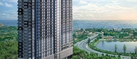 Um edifício alto com design arquitetônico moderno, cercado por vegetação e um corpo d'água.
