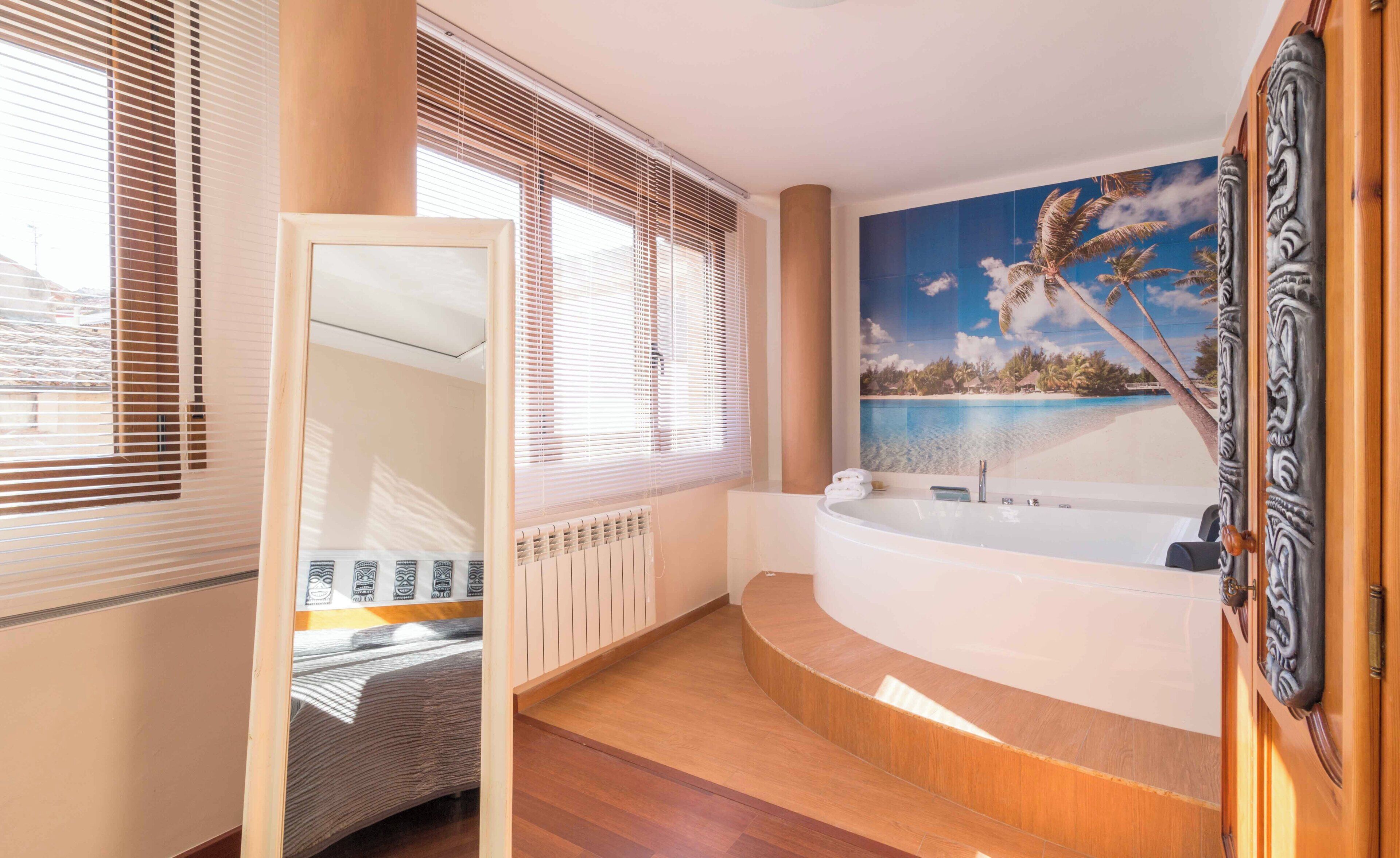 Um banheiro moderno com uma banheira grande, piso de madeira e um mural tropical na parede.