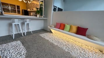 Um interior moderno com área de bar, assentos com almofadas coloridas e piso com padrão de pedrinhas.