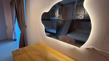 Quarto com cama beliche, mesa de cabeceira de madeira e janela com vista do aposento.