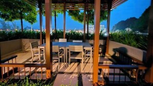 Uma área de estar ao ar livre com pérgola, mesas e cadeiras.
