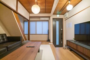 Uma sala de estar moderna com teto de madeira, um sofá, uma mesa de centro, uma televisão e uma porta de correr.