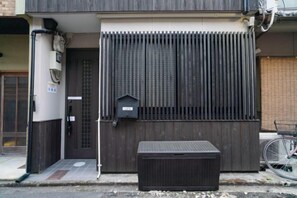 Uma entrada de edifício com um portão de madeira escura, uma caixa de correio e uma bicicleta estacionada.