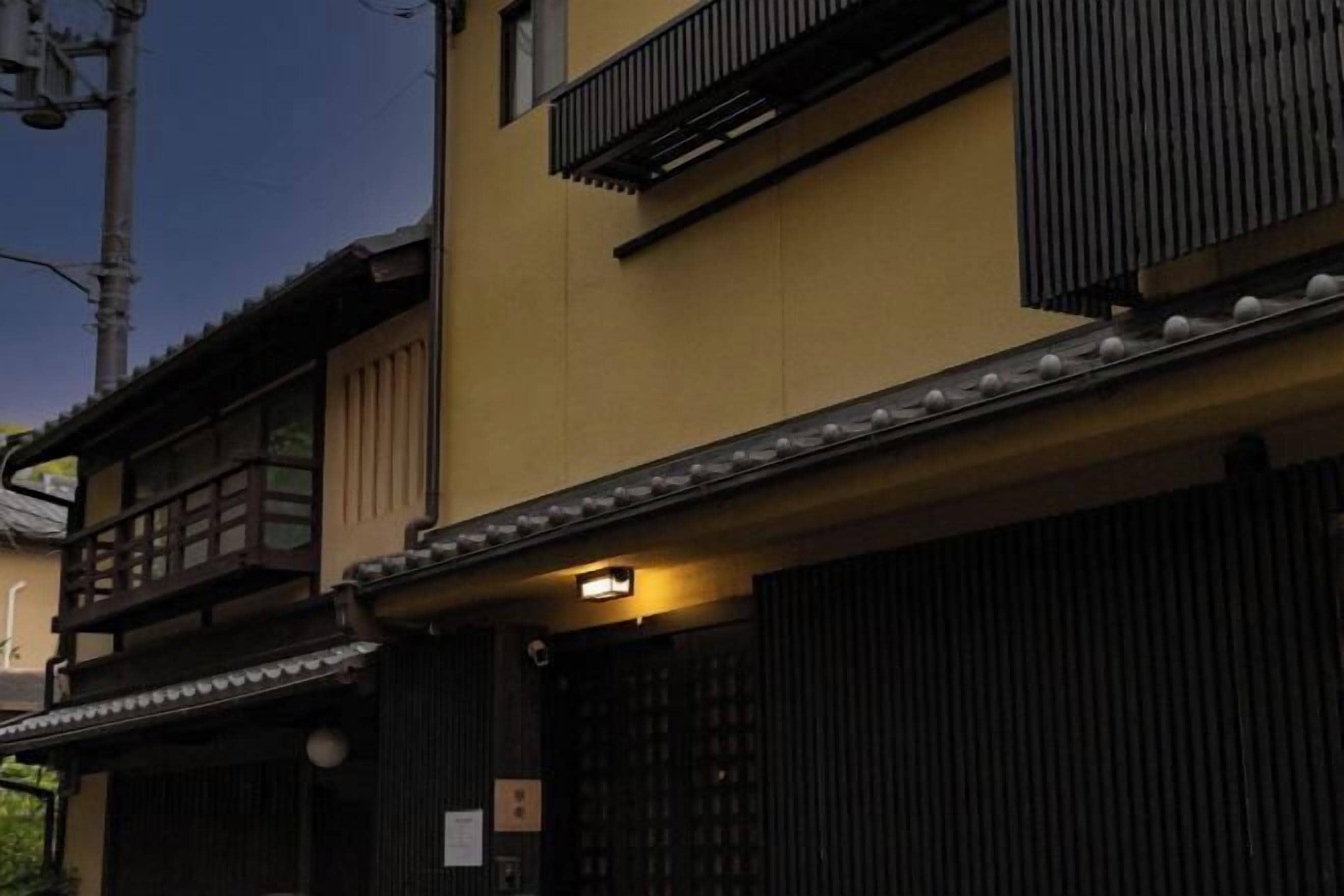 Um edifício tradicional japonês com varanda de madeira e portão preto.