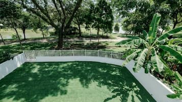 Área externa circular com guarda-corrimão branco, cercada por árvores e vegetação.
