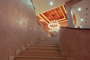 Uma escadaria com degraus de madeira e um candelabro no topo.