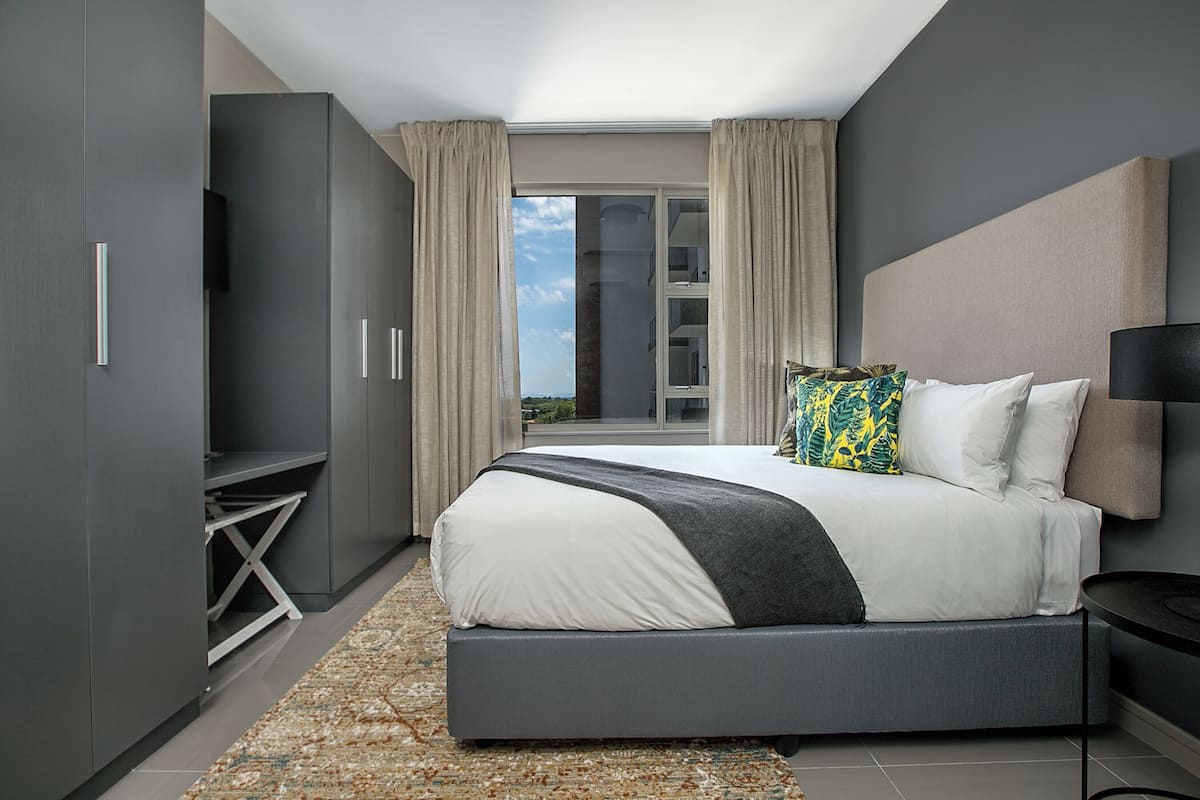Quarto moderno com uma cama grande, TV e vista para a varanda.