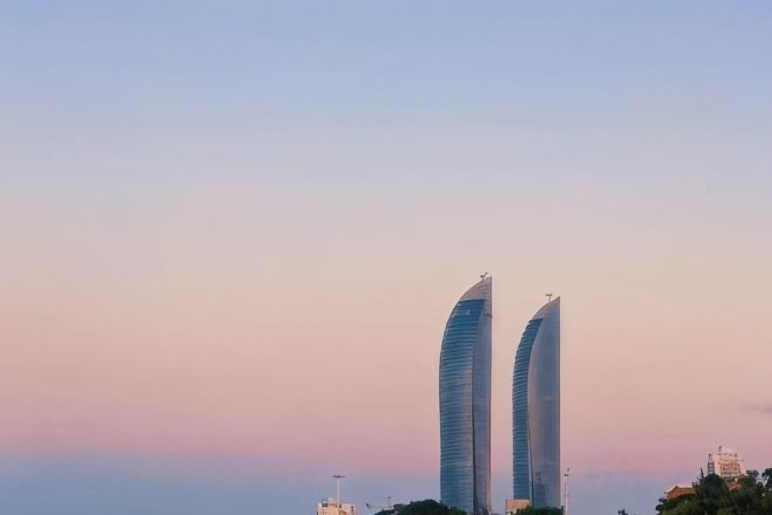 Dois edifícios altos com design curvo, ao fundo um céu limpo.