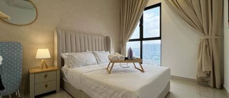 Quarto de hotel com uma cama grande, uma mesa de cabeceira com luminária, uma janela com cortinas e vista para a cidade.