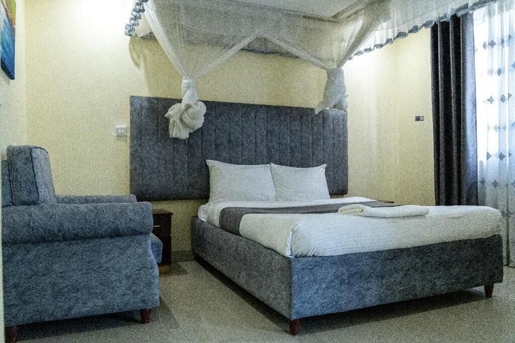 Um quarto com uma cama, uma cadeira e uma mesinha de cabeceira.