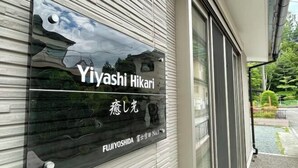 A building with a reflective glass sign displaying "Yiyashi Hikari" and "FUJIYOSHIDA".
