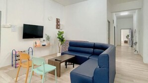 Uma sala de estar moderna com um sofá azul, uma televisão, uma mesa de centro e uma planta.