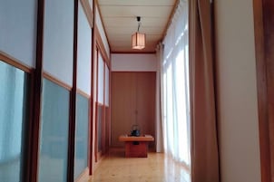 Um corredor com piso de madeira, um banco e um candelabro.