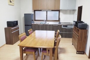 Uma cozinha compacta com mesa de jantar, cadeiras, geladeira e micro-ondas.