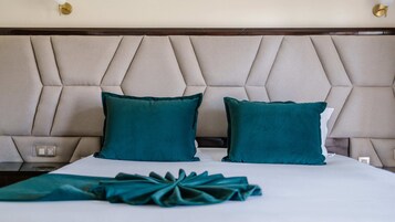 Uma cama com cabeceira estofada, duas almofadas verde-água e um cobertor verde-água dobrado.