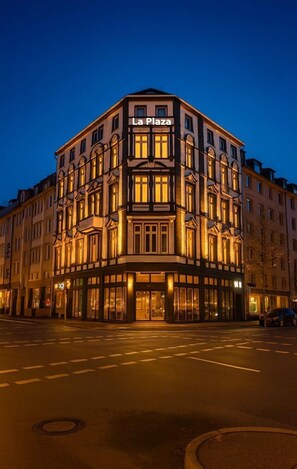 Um hotel com vários andares, entrada imponente e sinalização iluminada.