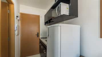 Uma cozinha compacta com micro-ondas, geladeira e porta de madeira.