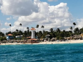 Uma praia com uma torre listrada, palmeiras e um quiosque.