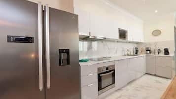 Cozinha moderna com geladeira de aço inoxidável, micro-ondas e forno embutido.