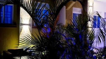 Quarto com uma janela grande, uma planta em primeiro plano e vista para o exterior.