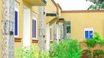 Edifício com várias varandas, fachada amarela e área de jardim com plantas e estrutura de madeira.